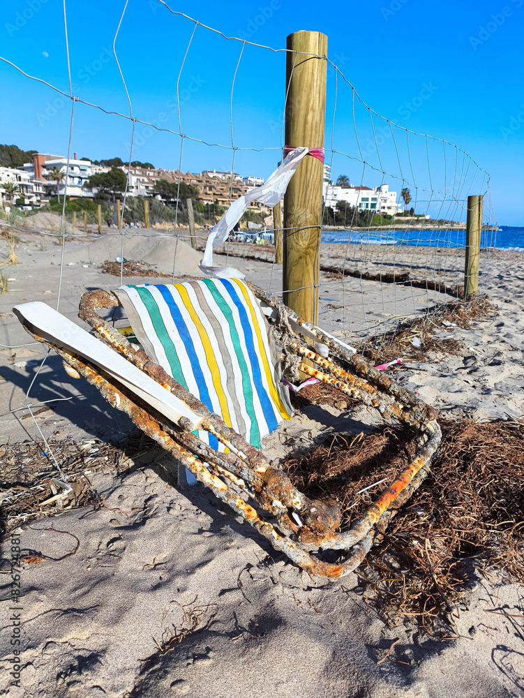 Broken beach chair lying on the beach. Pollution and garbage. Incivic ...