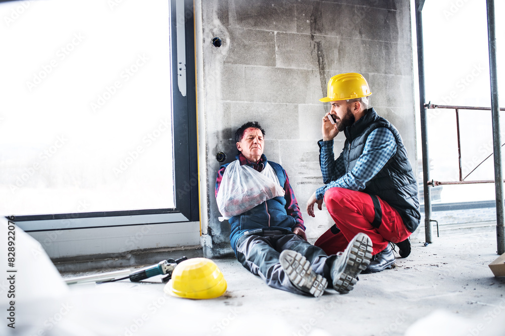 Colleague calling ambulance and giving first aid to injured worker, in ...