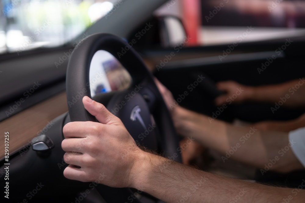 Behind steering wheel Tesla model Y electric car, male hands on Driver ...