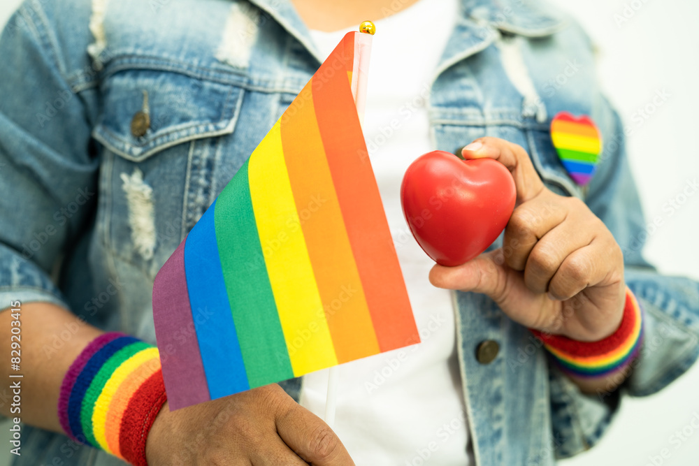 Asian lady wearing rainbow flag wristbands and hold red heart, symbol ...
