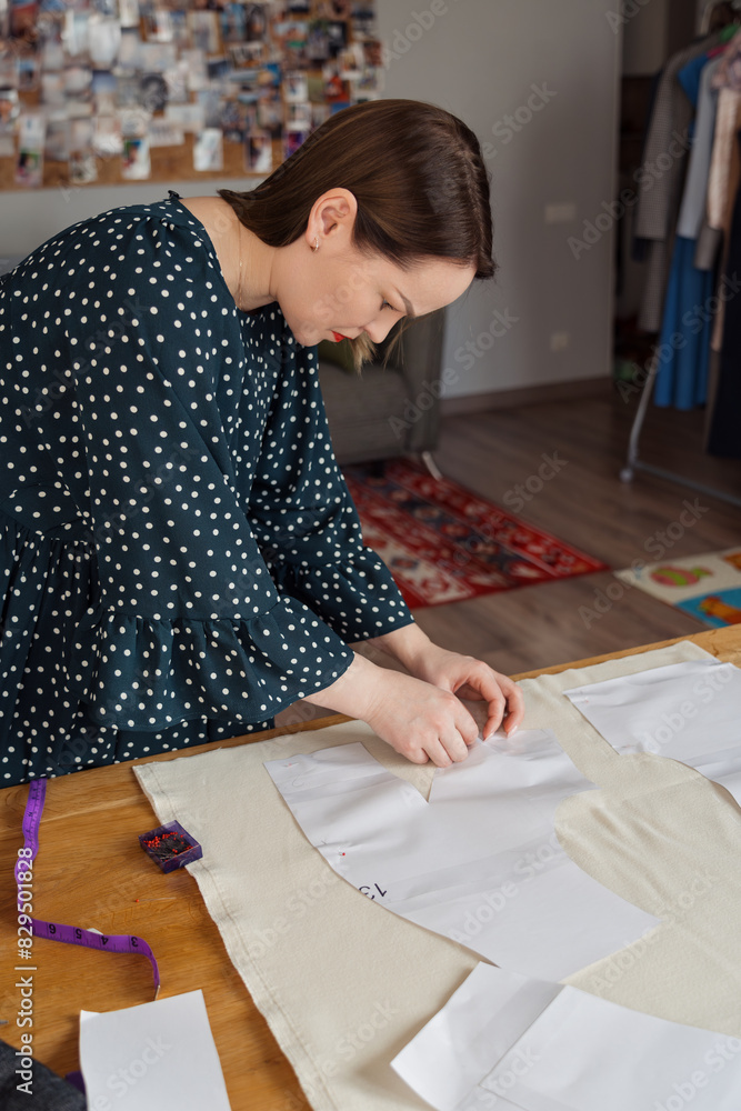 Focused fashion designer tracing patterns for a new garment on fabric ...
