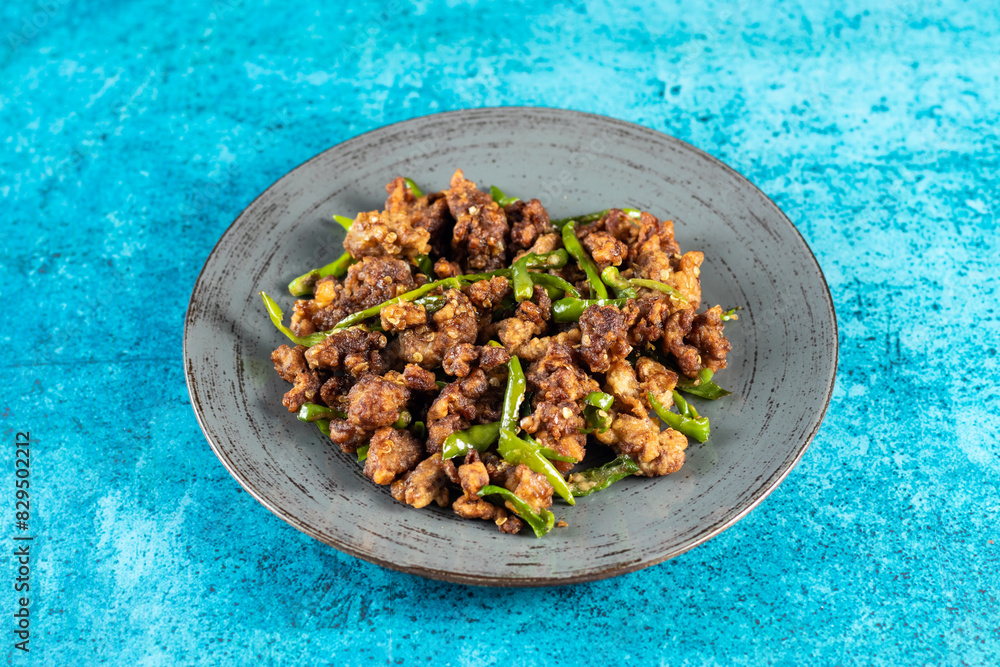 Stir Fried Green Chilli Chicken Dry served in plate isolated on blue ...