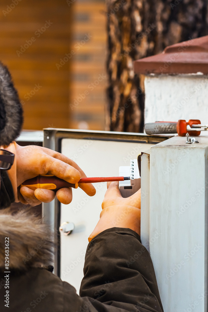 An electrician changes a circuit breaker in an electrical panel ...