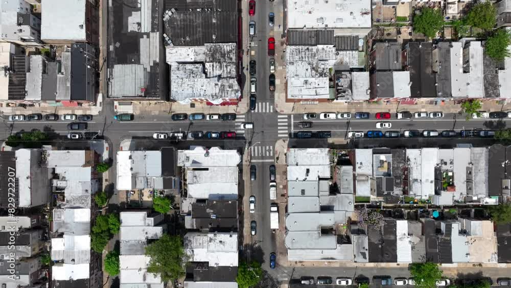Busy urban intersection with dense row houses, parallel parking, and ...