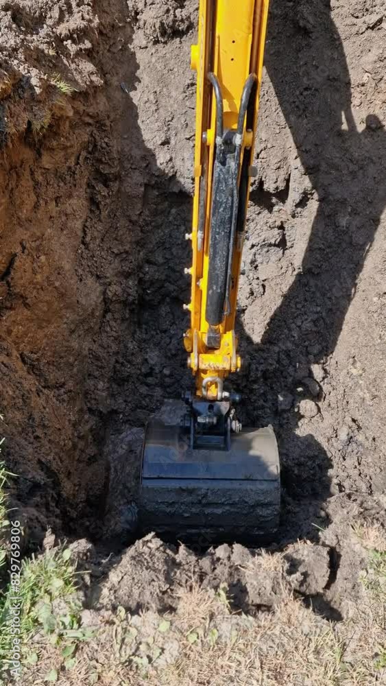 Vertical video. The bucket of the excavator digs a hole where the water ...