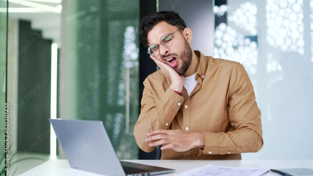 Upset worker suffering from toothache working on laptop sitting at ...