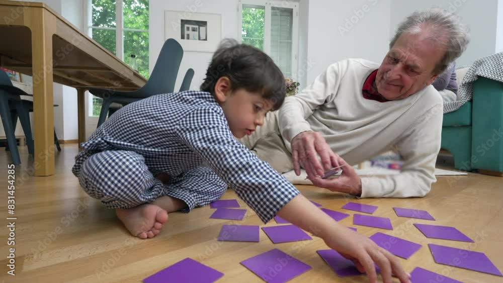 Grandfather lying on the floor and playing a matching game with his ...
