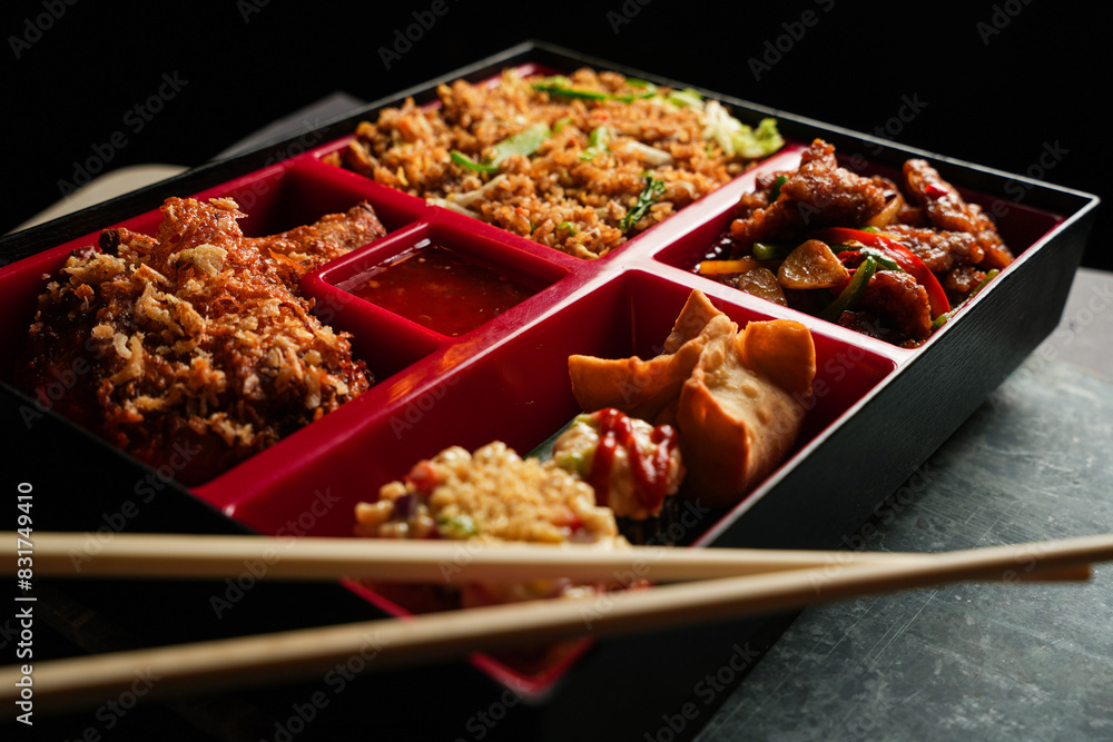 Bento box on a grunge black background with chopsticks, Containing ...