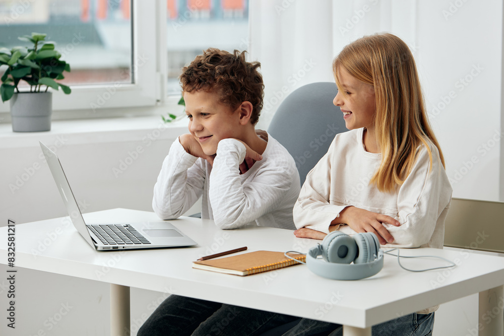 Happy children studying at home with laptops, headphones, and tablets ...