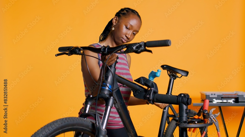 BIPOC mechanic setting up bike repair stand, using it to adjust ...
