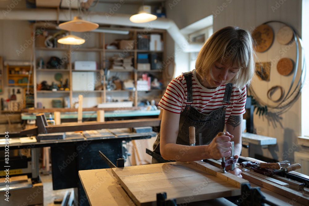 Concentrated female carpenter working on gluing wooden planks together ...