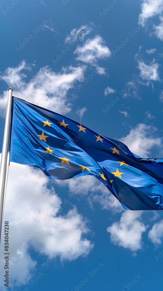 European Union flag waving against a clear blue sky with clouds ...