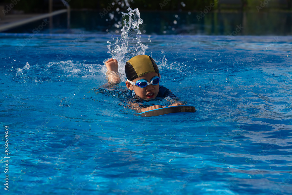 6 years old young Asian boy who a swimmer wearing goggle with dark blue ...