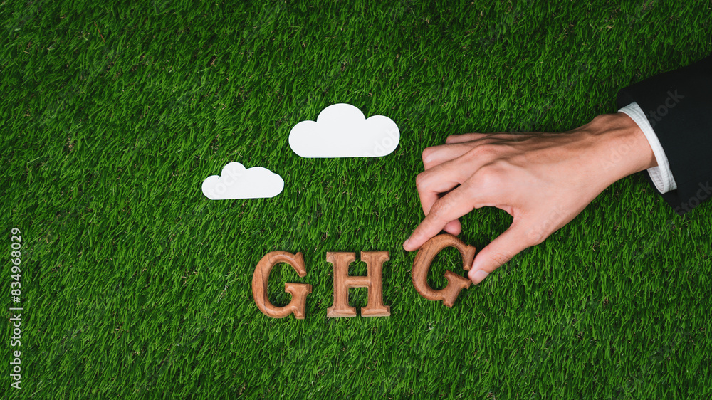 Hand arrange wooden alphabet text in GHG on biophilic background with ...