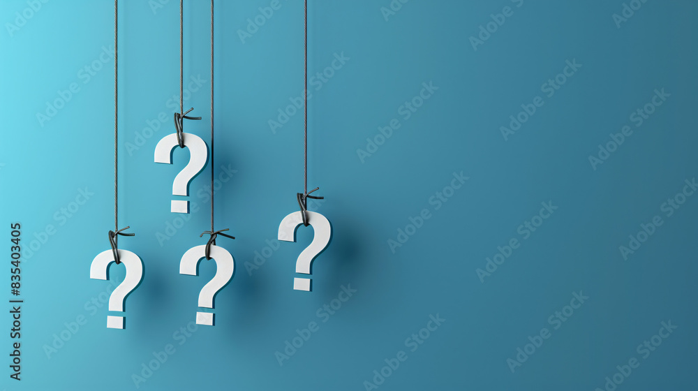 White question marks hanging on strings against a bright blue ...