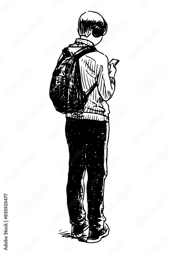 Teen boy alone, using phone, looking at phone, back view,headphones ...