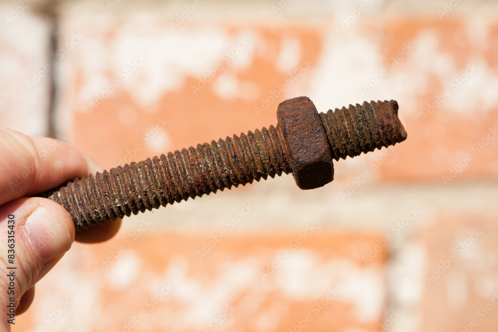old rusty bolt, iron rod with screw threads, in hand. Rusted mechanical ...