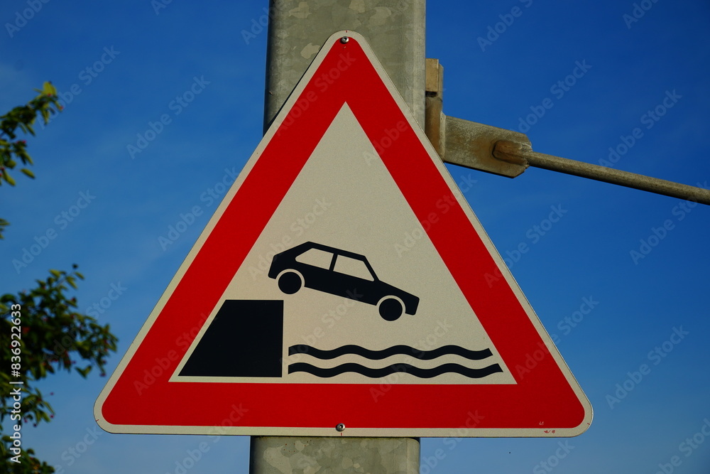 German and european road sign showing a car driving into water, warning ...