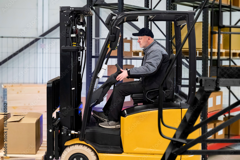 Man operates forklift. Guy works in warehouse. Driver driving forklift ...