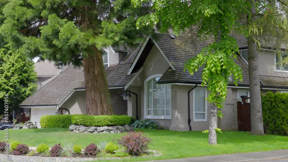 Establishing shot of two story stucco luxury house with big tree and ...