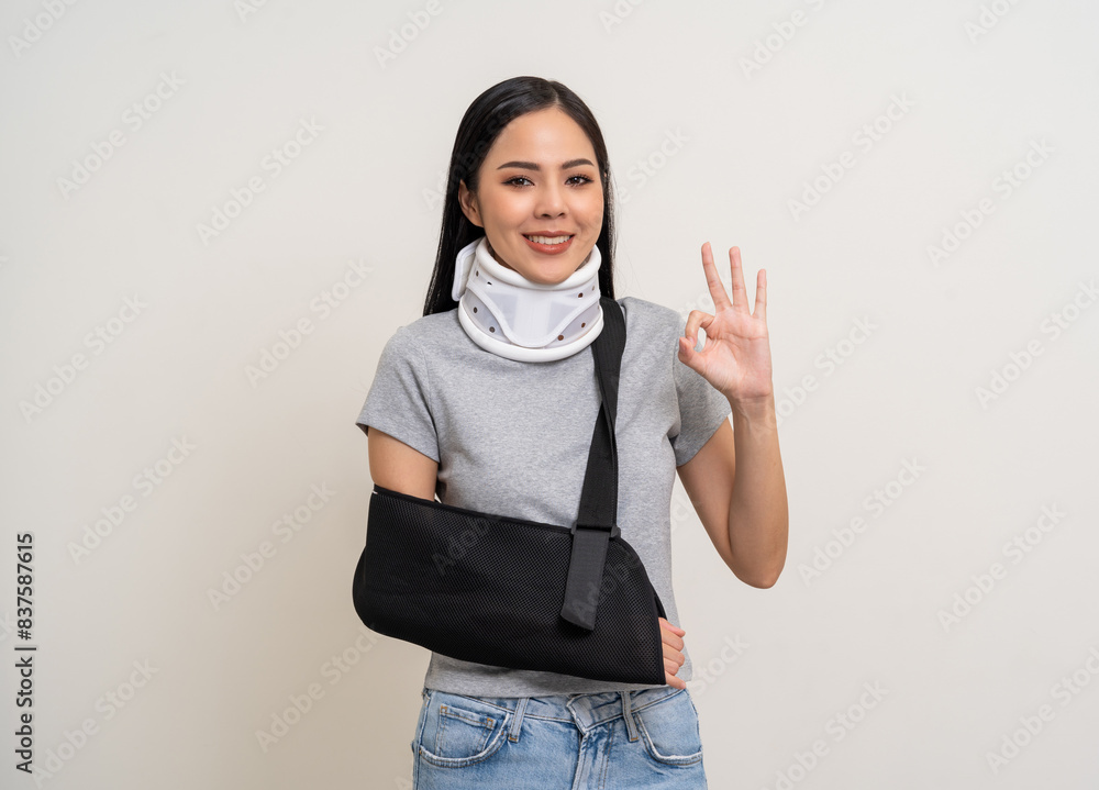 Happy young asian woman broken arm on isolated background. Asian female put on plaster bandage ...