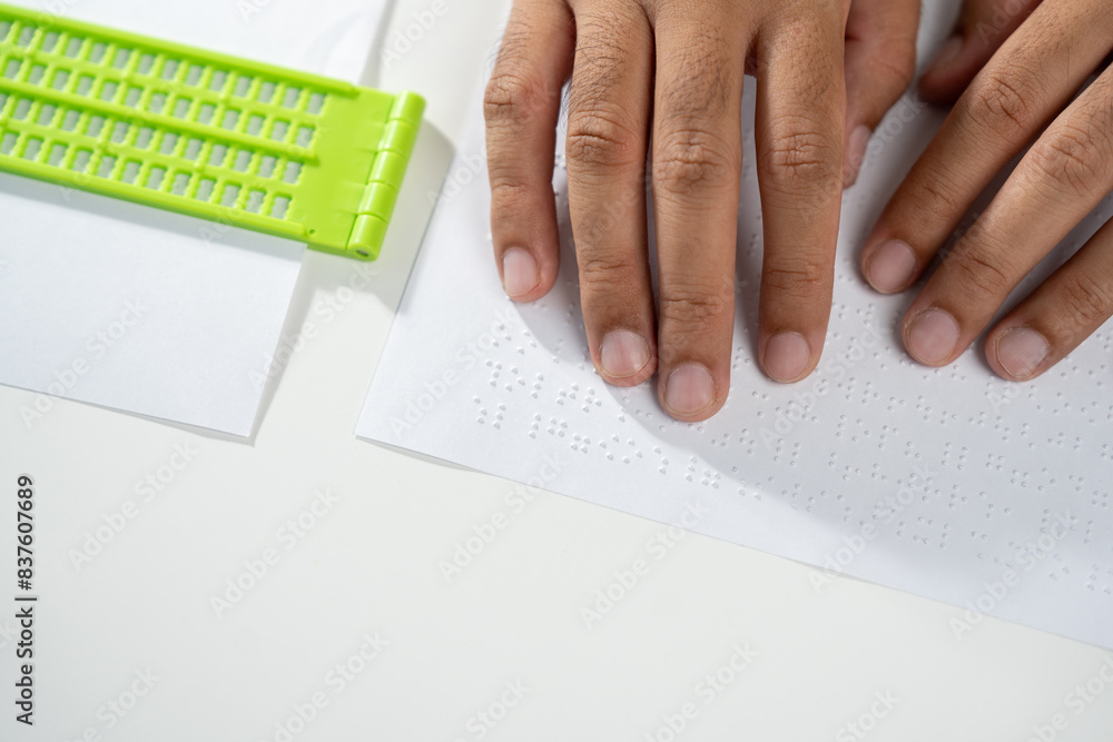 Hand of a blind person reading some braille text on page paper to learn ...