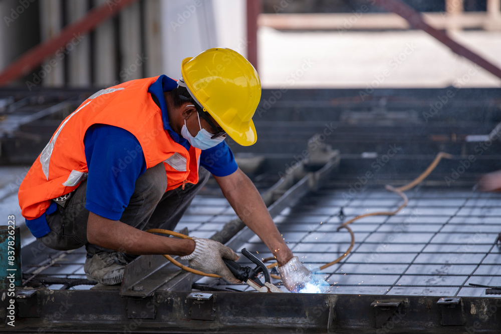 Construction worker engaged in welding work. He is crouching down on a ...