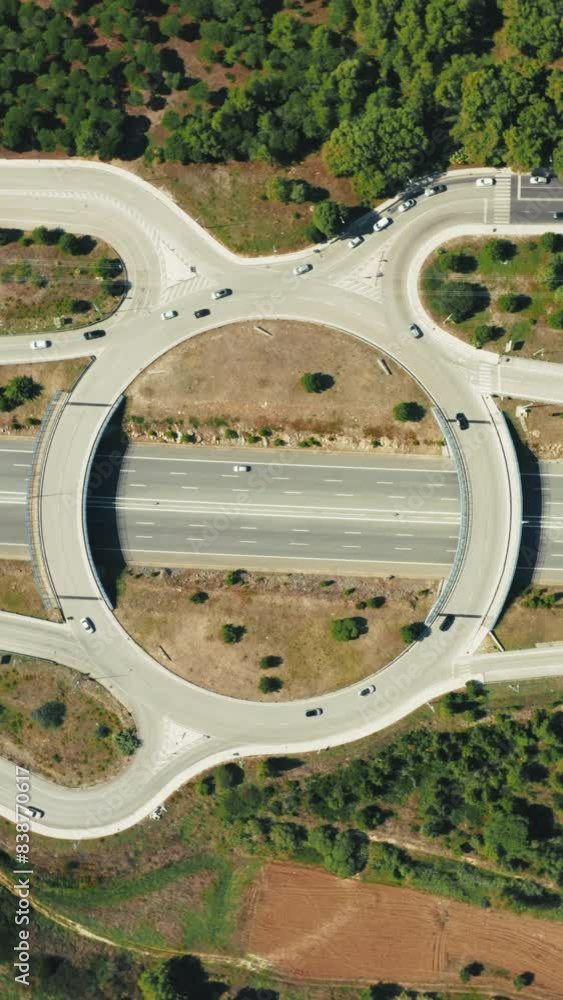 Vertical video of a circular highway intersection surrounded by ...