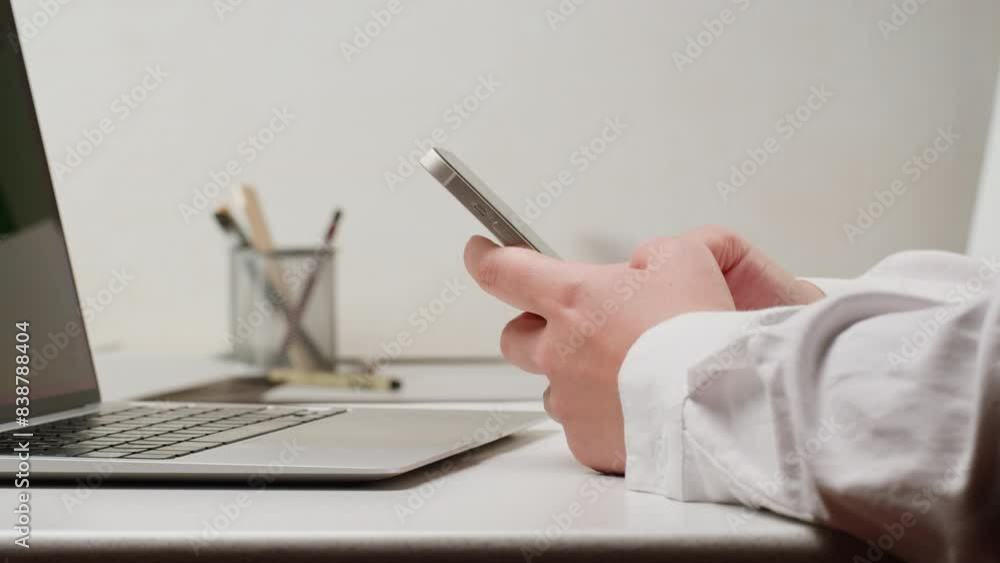 Young woman is staring and typing at phone in office workplace. Work ...