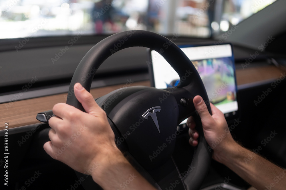Behind steering wheel Tesla model Y electric car, male hands on Driver ...