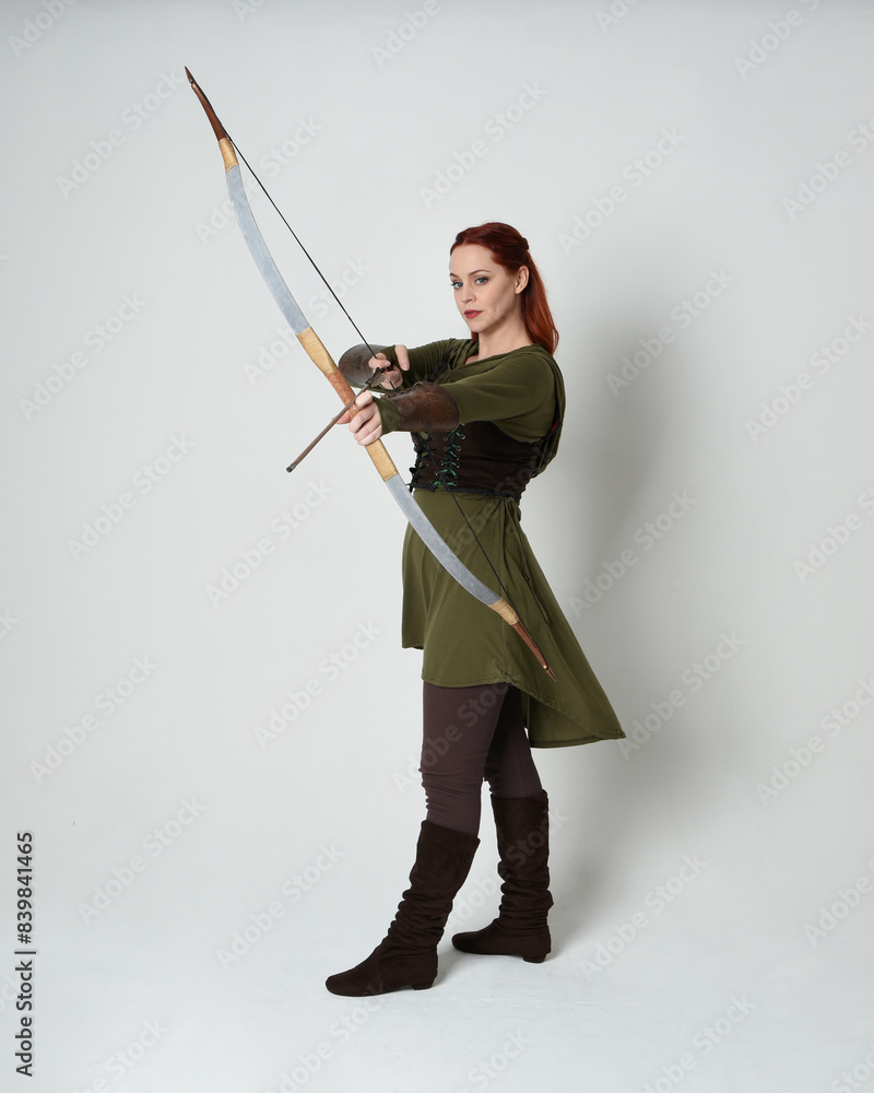 Full length portrait of red haired female model wearing green medieval ...