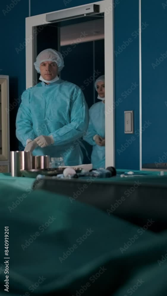 Two professional surgeons in uniforms, gloves, masks and hats enter the ...