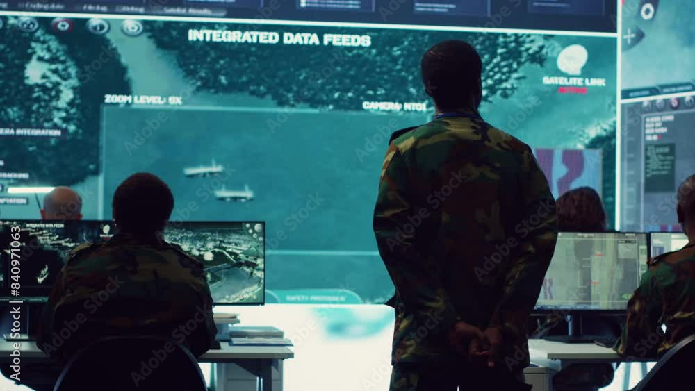 Staff sergeant monitoring satellite live imagery on a big screen ...