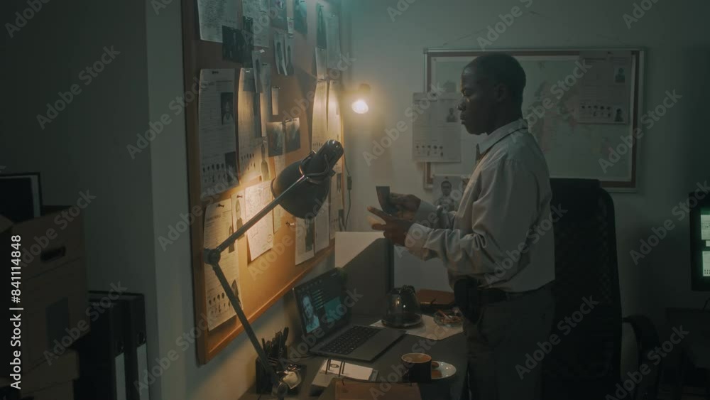 Medium tracking shot of African American police detective picking up ...