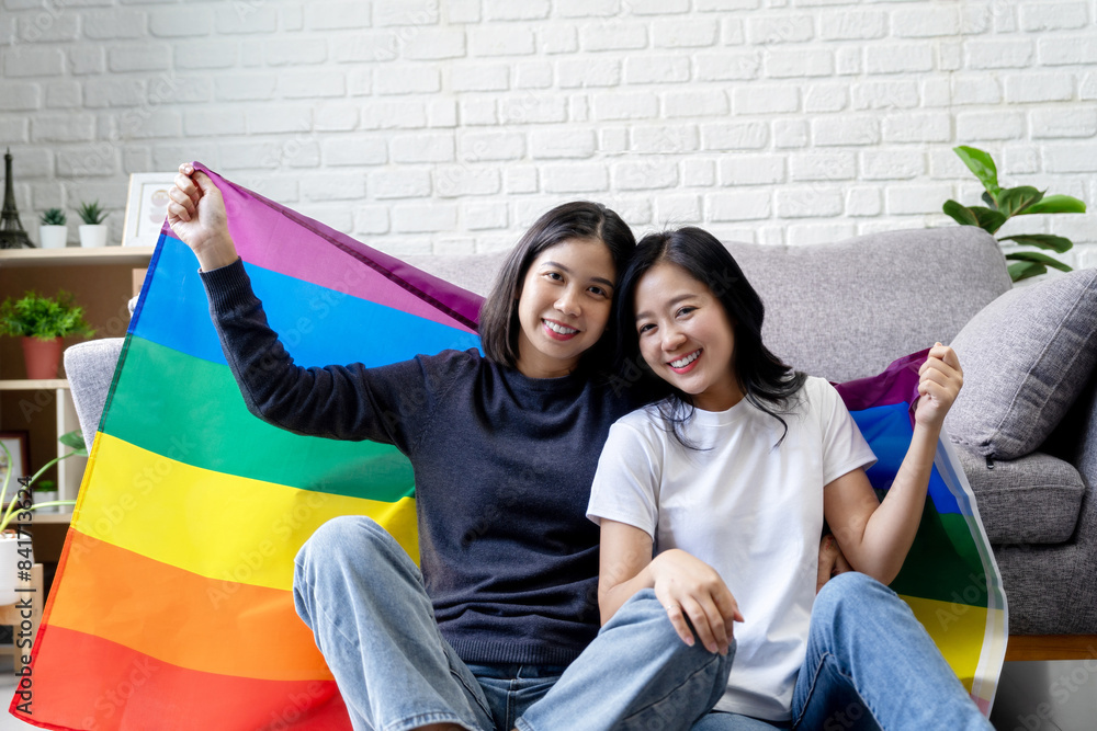 Two beautiful young Asian lesbians in casual clothes sitting on the living room floor and ...