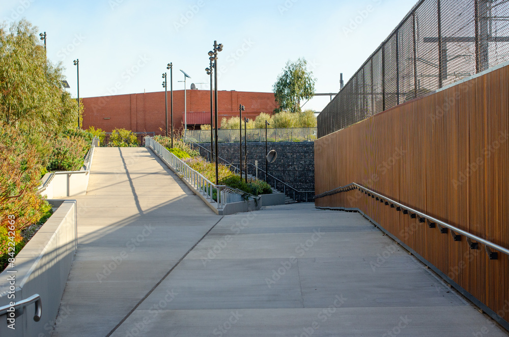 An urban concrete pedestrian walkway with wooden panels and metal ...