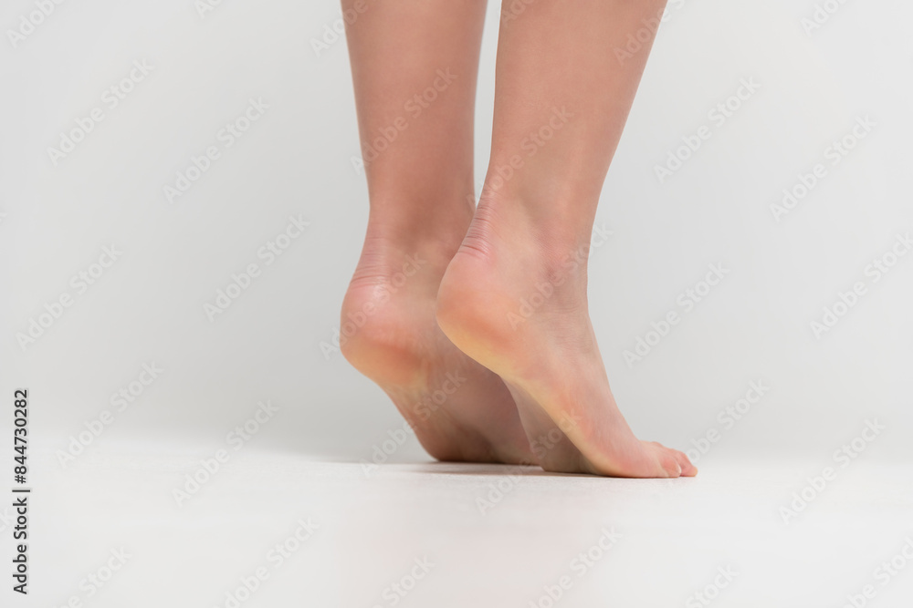 Close-up rear view of barefoot woman standing on white floor and ...