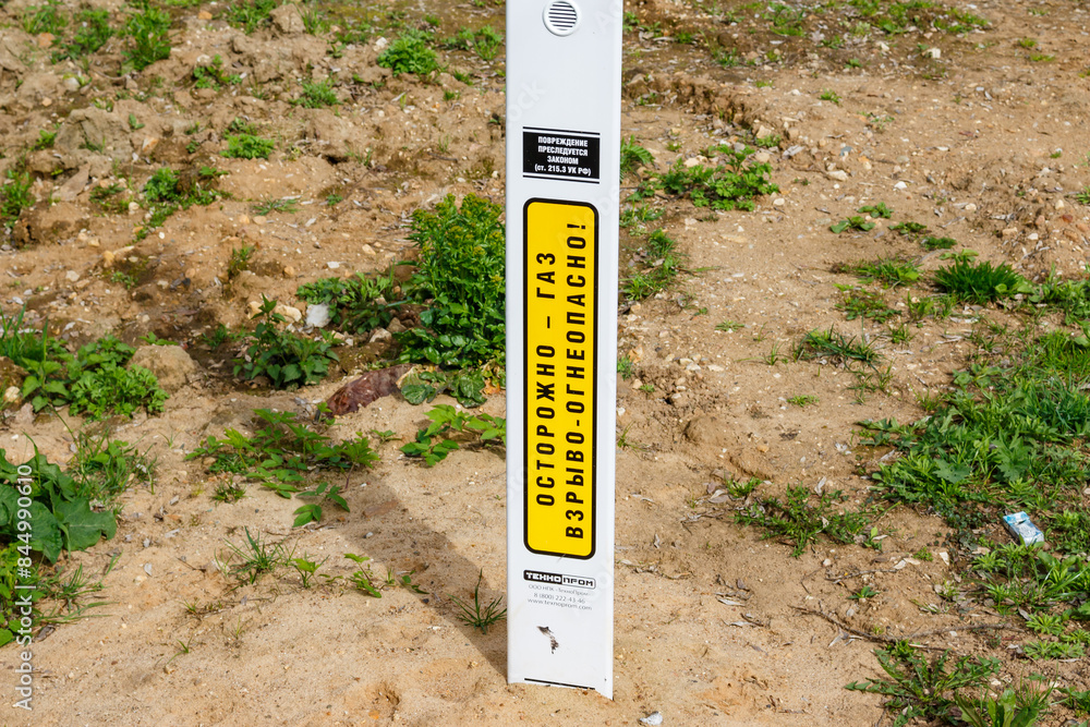A pole installed on a gas pipeline. Bright inscription Caution Gas ...