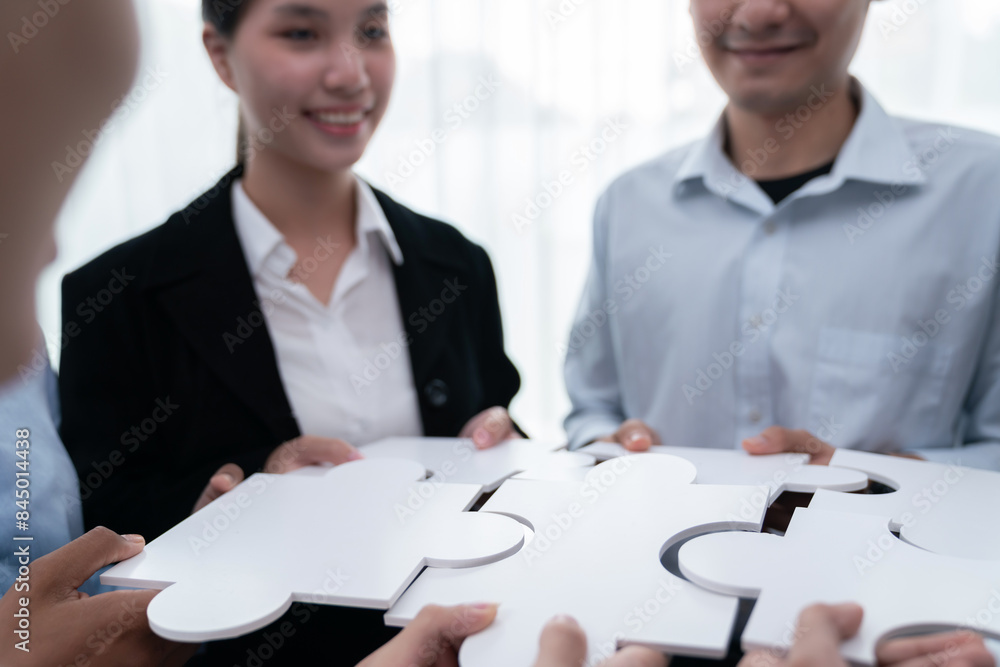 Diverse corporate officer workers collaborate in office, connecting puzzle pieces to represent ...