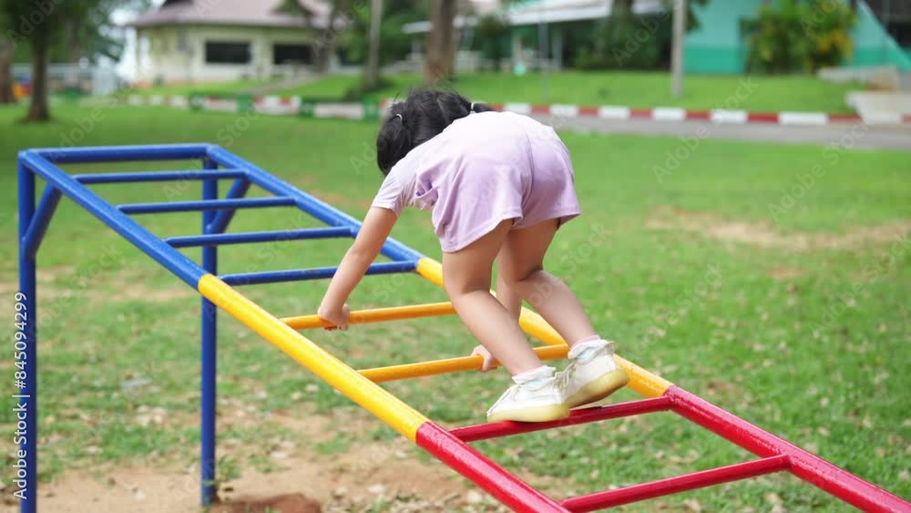 Asian little girl is climbing a ladder on a playground. She is wearing ...