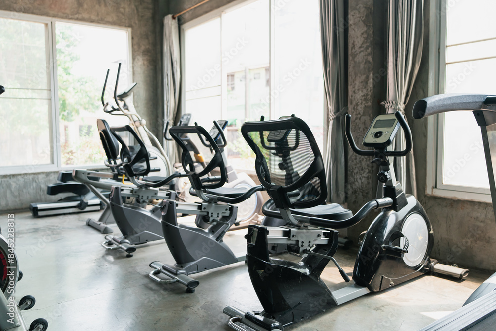 A row of exercise bikes are lined up in a gym. The bikes are all ...