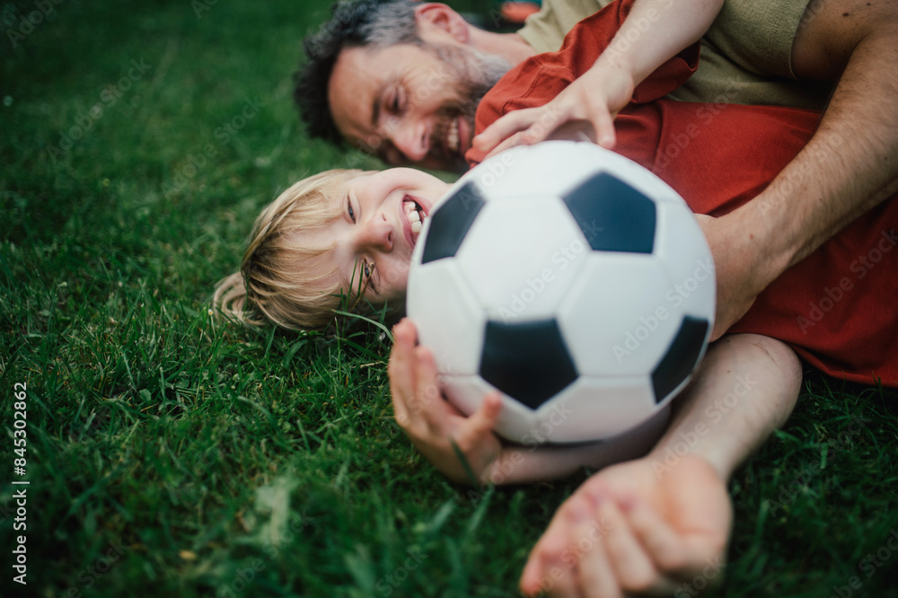 Dad lying on grass with son, laughing and having fun. Father and boy ...