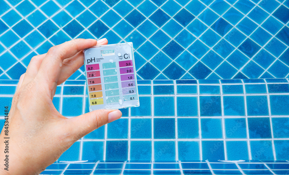 Girl hand holding swimming pool tester with space on clear swimming ...