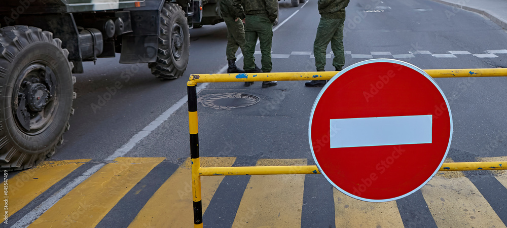 Armed soldiers standing near a roadblock with a no entry sign in the ...