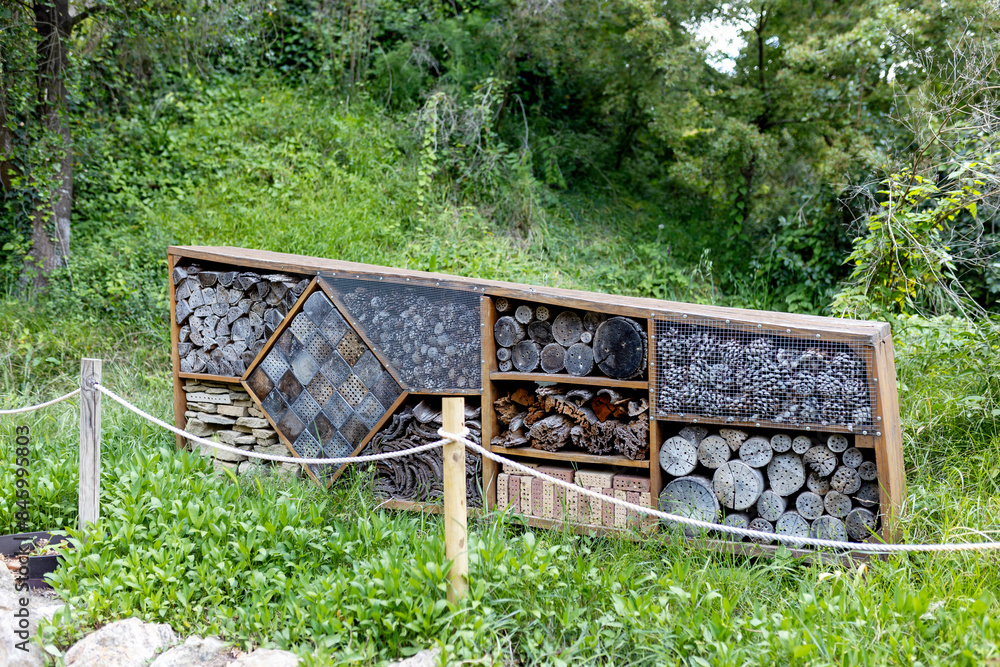 An insect hotel or bee hotel in a summer garden. An insect hotel is a ...