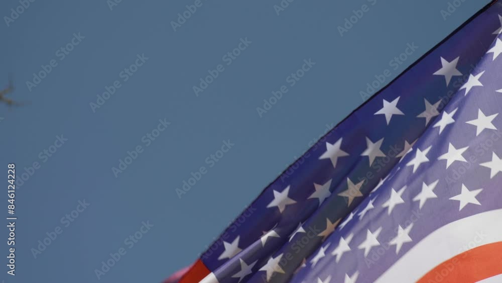 Against clear blue sky, US National Flag and Rainbow LGBT Flag fly ...