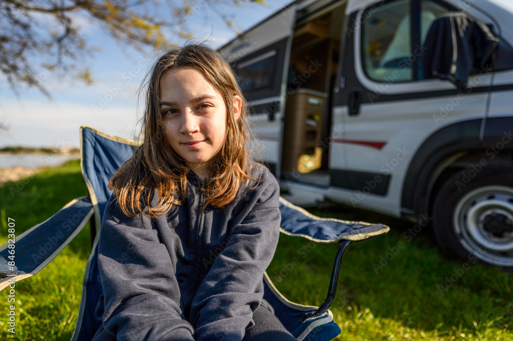 Girl sitting in front of campervan or motorhome parked on the beach ...