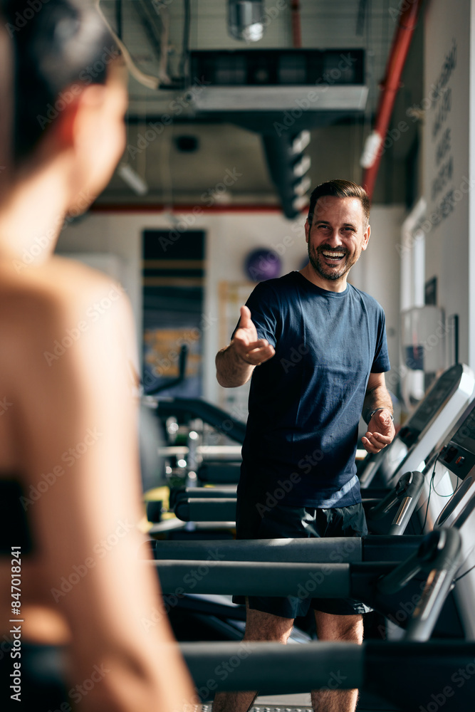 Gym partner talking with a female while both using a treadmill, at the ...