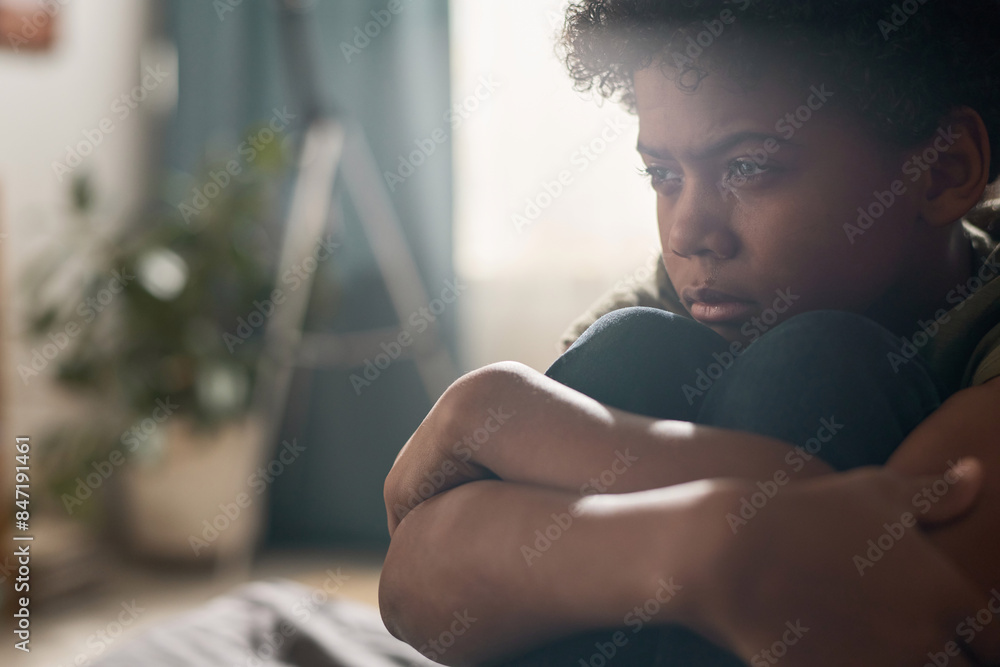 Dramatic close up portrait of Black boy crying and hugging knees in ...