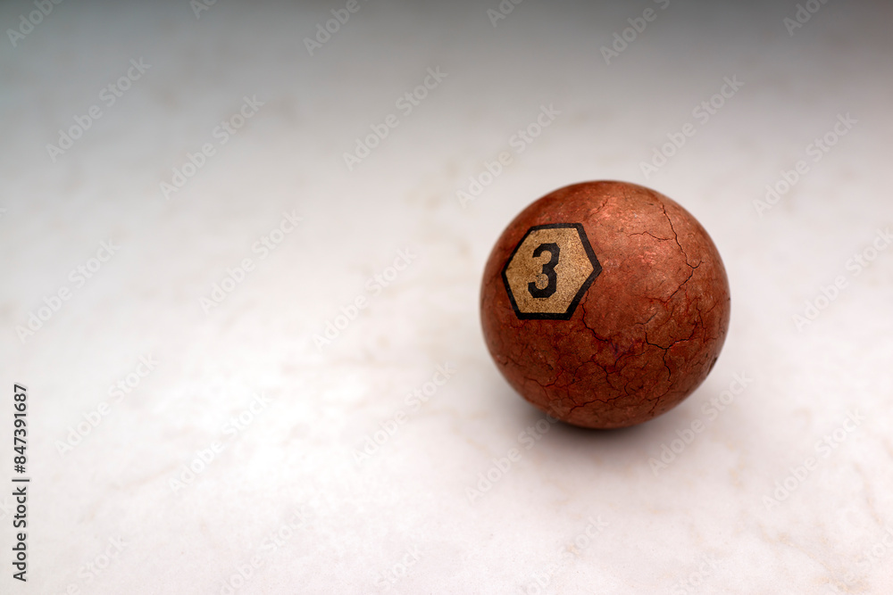 Vintage billiard ball. Red number 3 pool ball. Cracked clay surface and ...